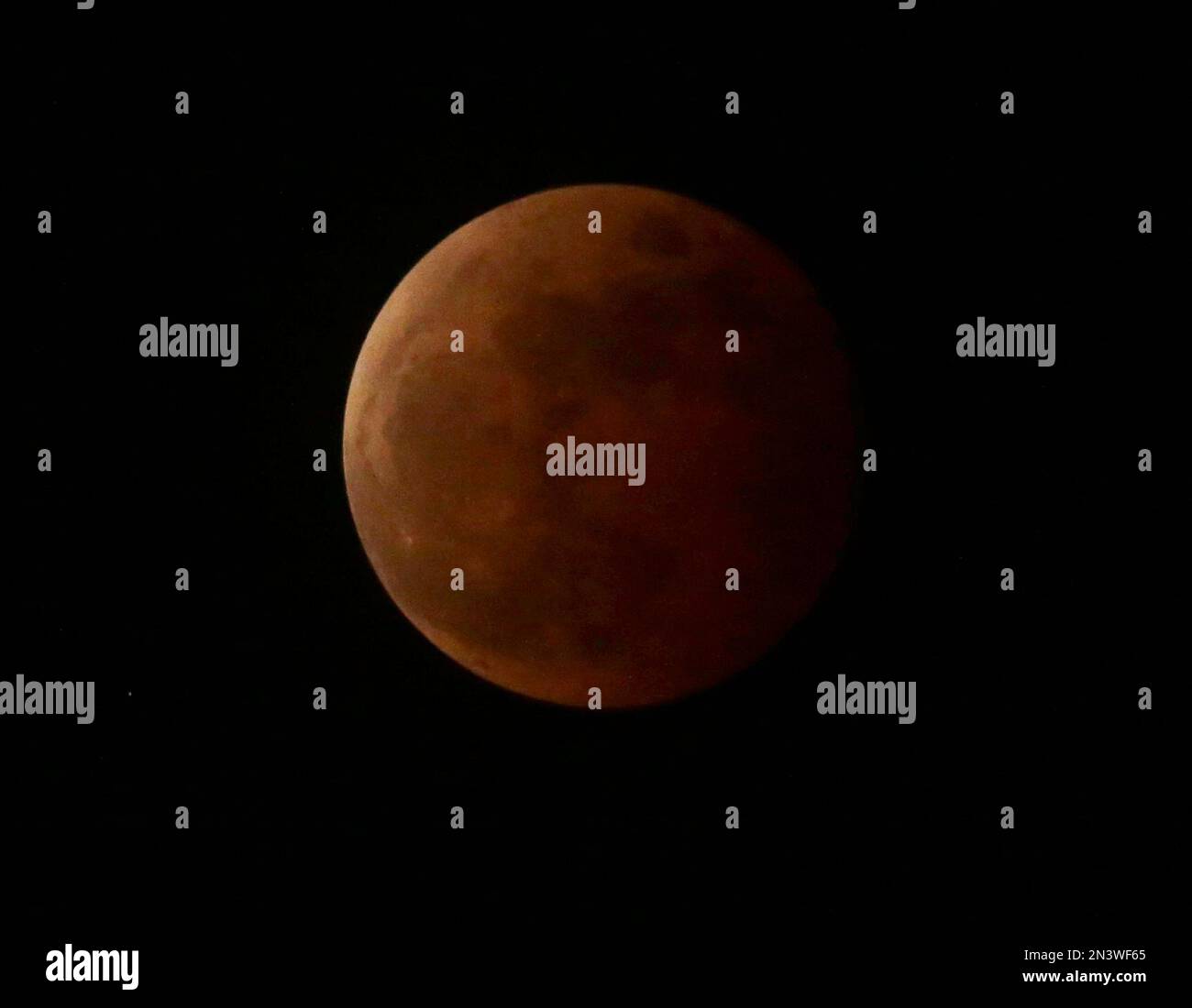 A deep orange moon appears in the sky during a total lunar eclipse ...