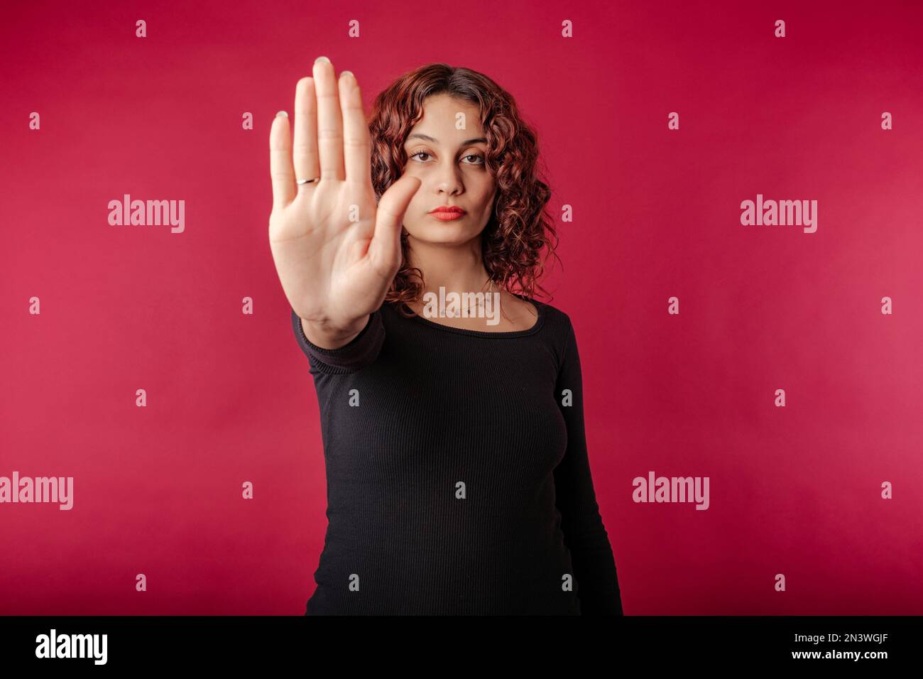 Redhead millennial woman wearing black dress standing isolated over red ...