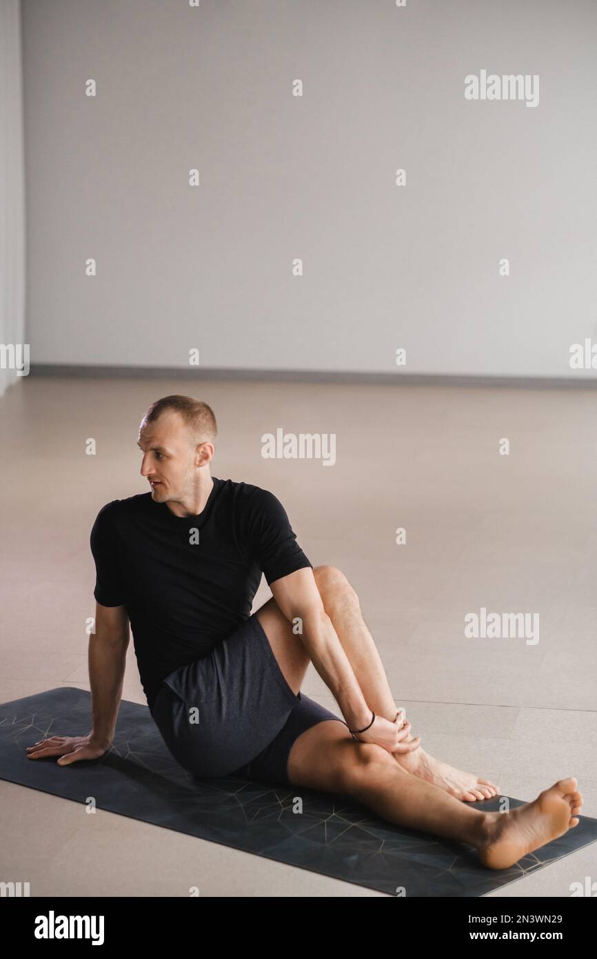 An athletically built man does yoga in the gym on a mat Stock Photo - Alamy