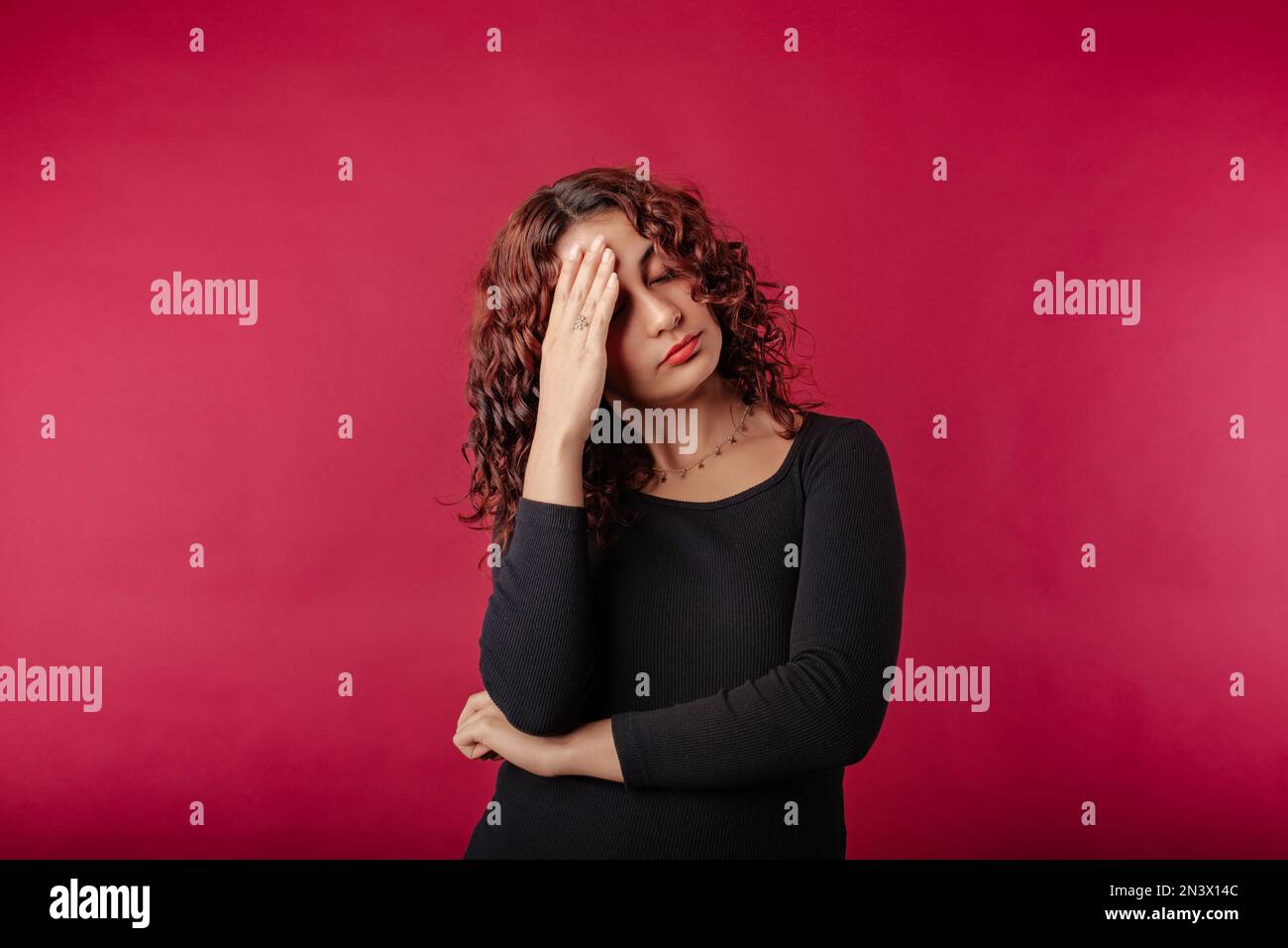 Woman wearing black ribbed dress standing isolated over red background ...