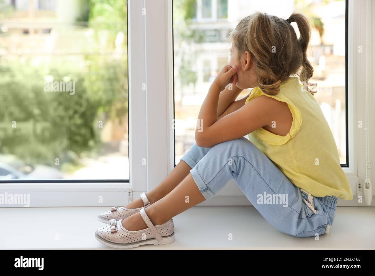 Cute little girl on window sill at home Stock Photo - Alamy