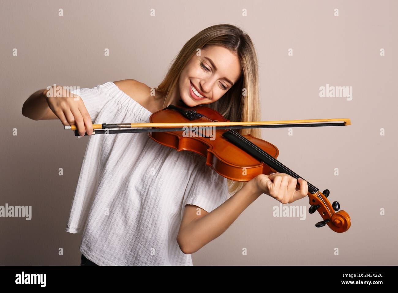 Beautiful woman playing violin on beige background Stock Photo - Alamy