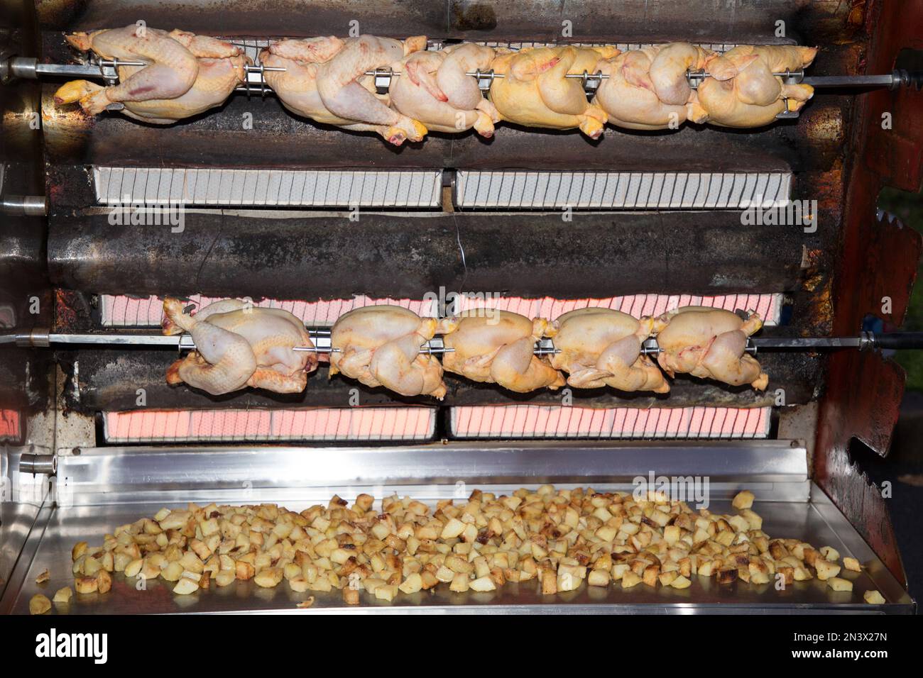 chickens cook in a roaster with potatoes on the market Stock Photo - Alamy