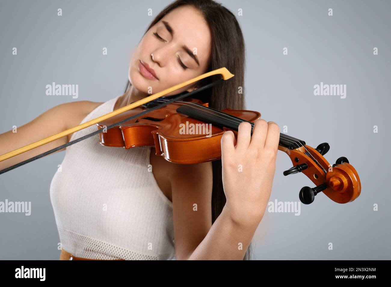 Beautiful woman playing violin on grey background, focus on hand Stock ...