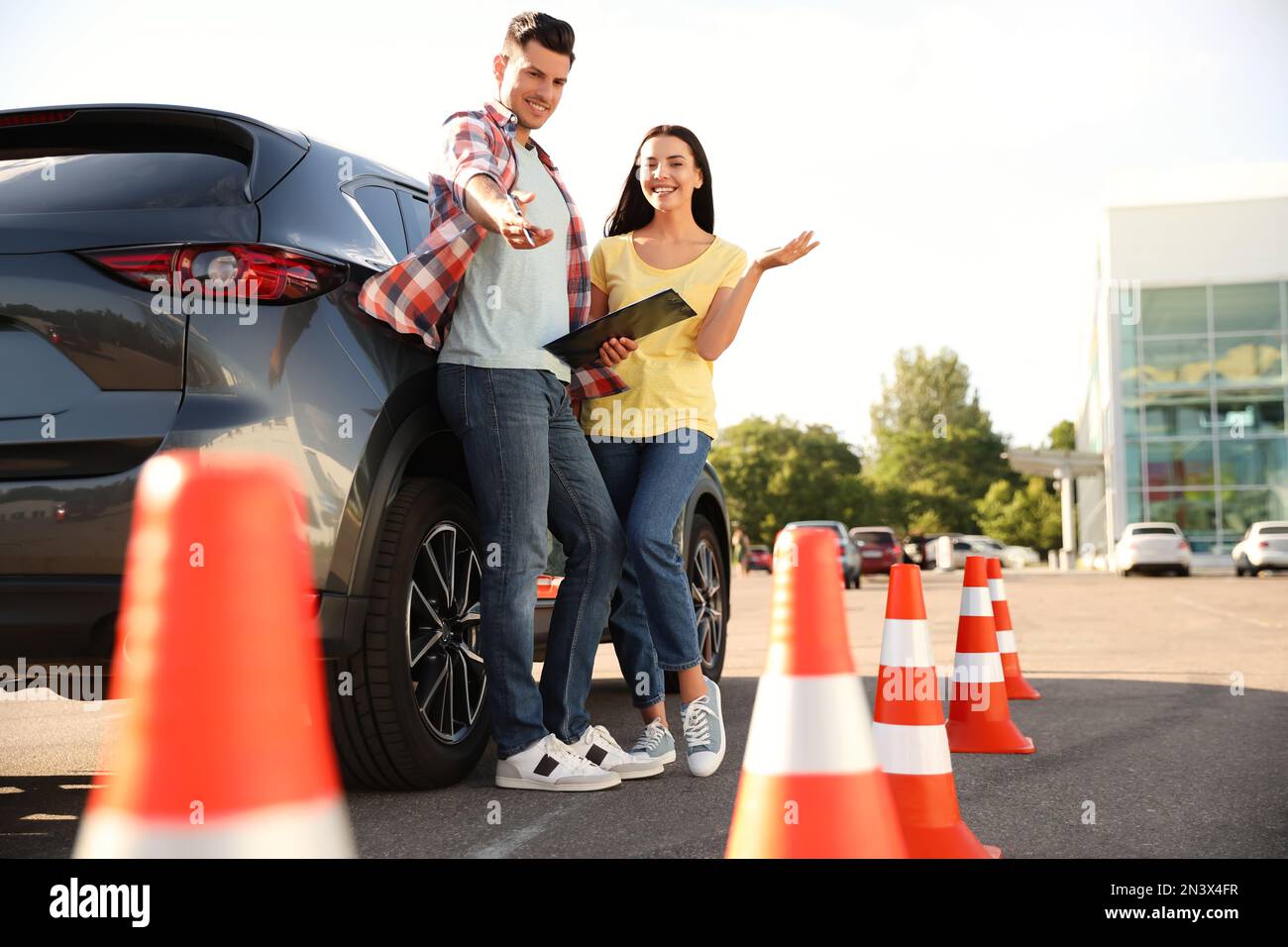 Instructor with clipboard and his student near car outdoors. Driving ...