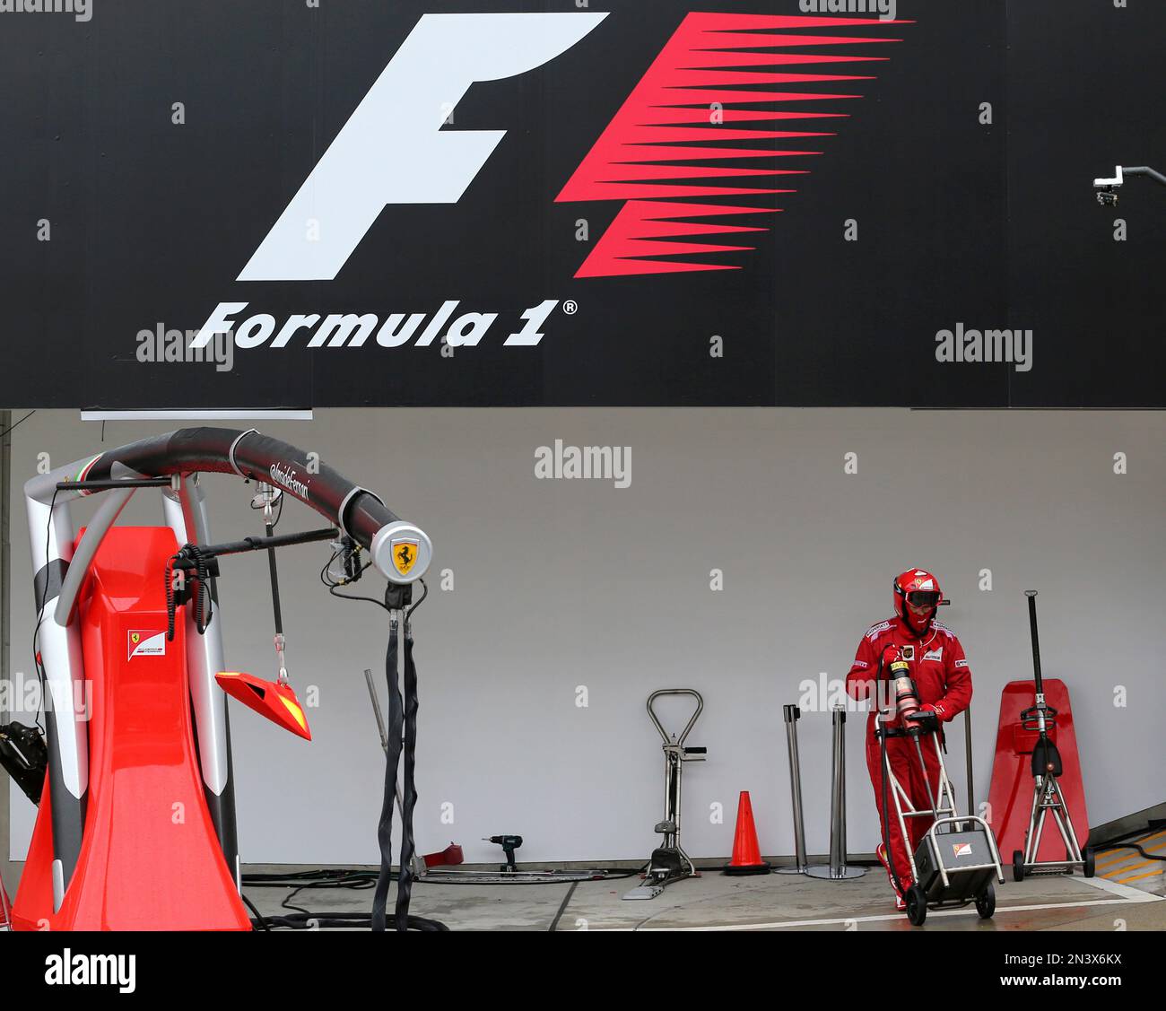 A crew member of Scuderia Ferrari works under a board reading Formula 1 ...
