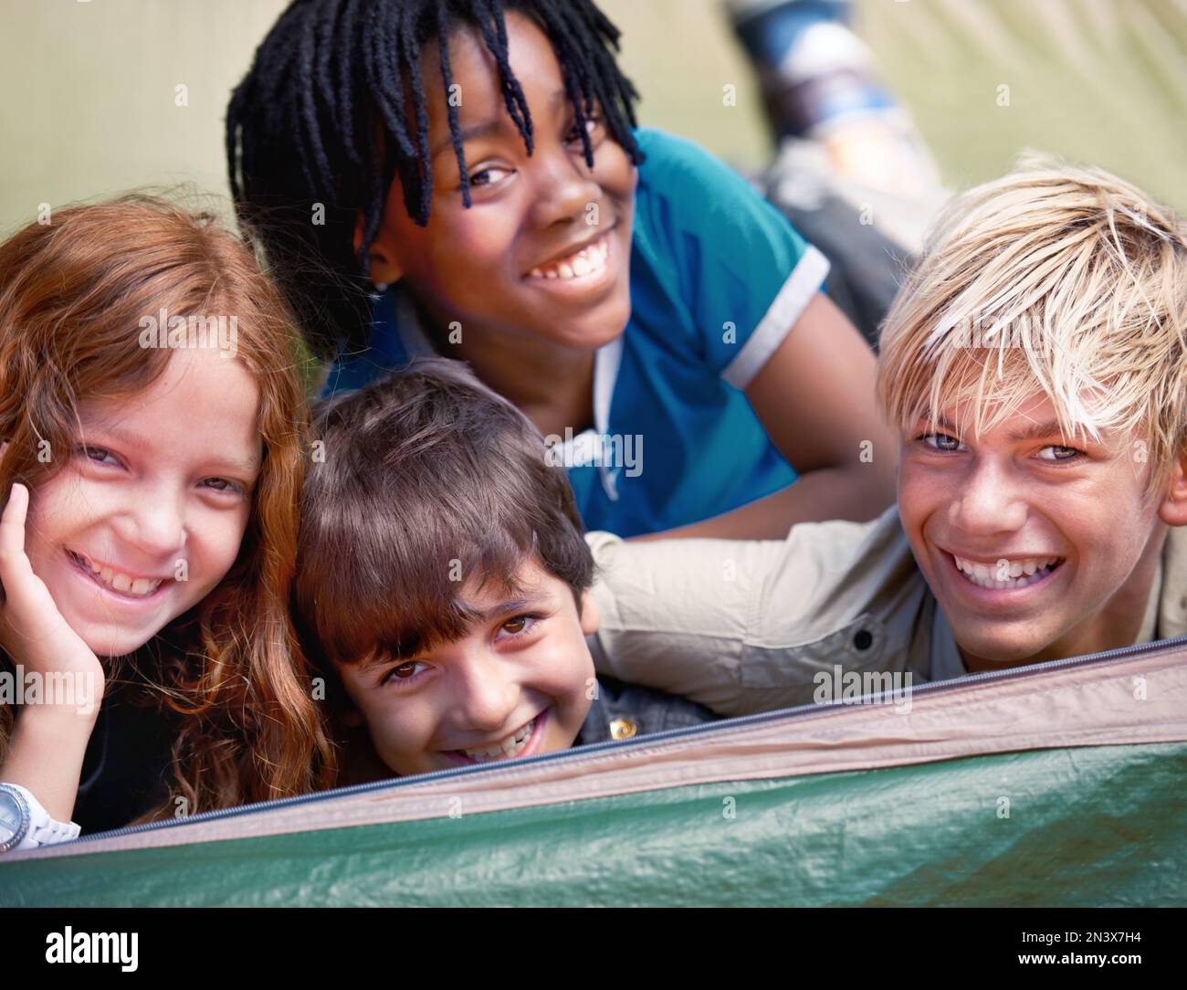 We love camping. Four friends lying in a tent together and smiling ...