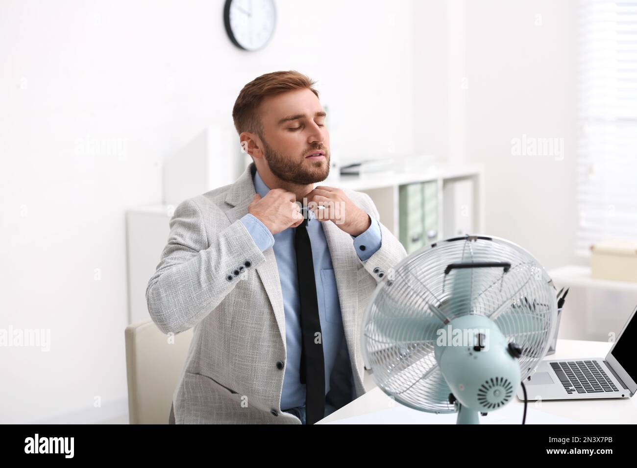 Man enjoying air flow from fan at workplace Stock Photo - Alamy