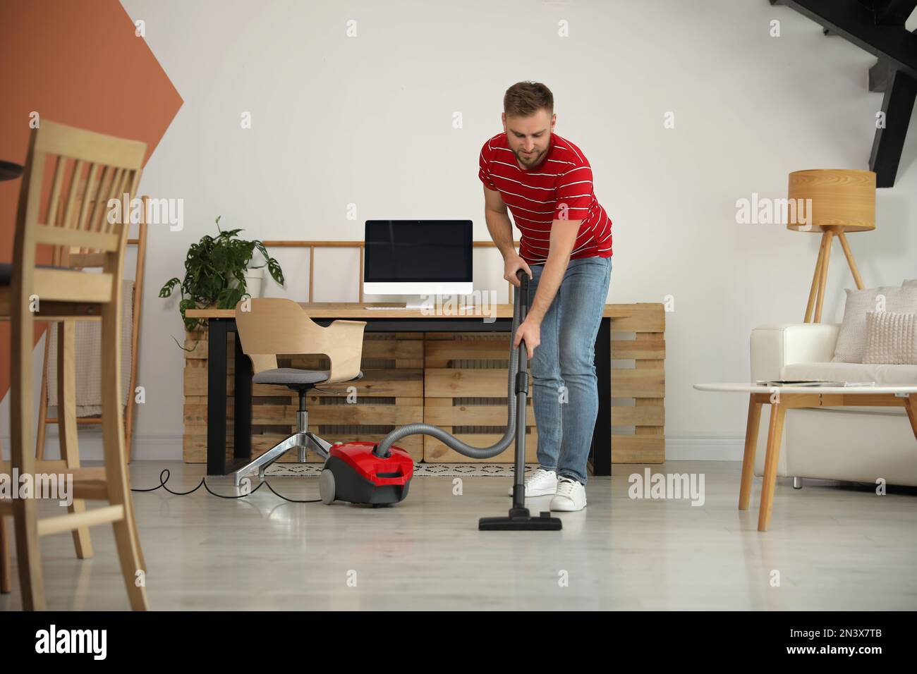 Young man using vacuum cleaner at home Stock Photo - Alamy