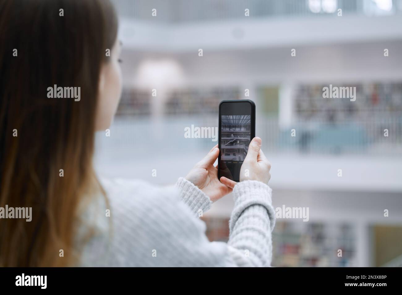 Phone, photography and student in library for research update, social ...