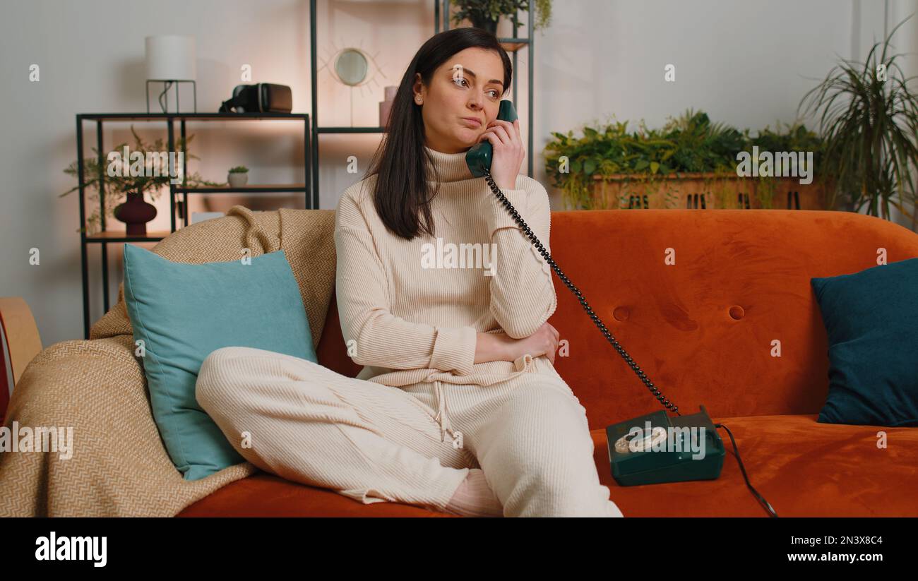 Bored tired young woman at home apartment talking on wired vintage ...