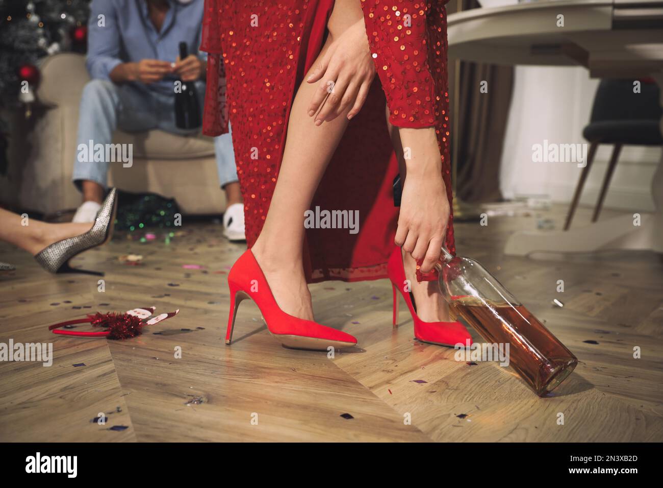 Woman with bottle of alcohol in messy room after New Year party ...