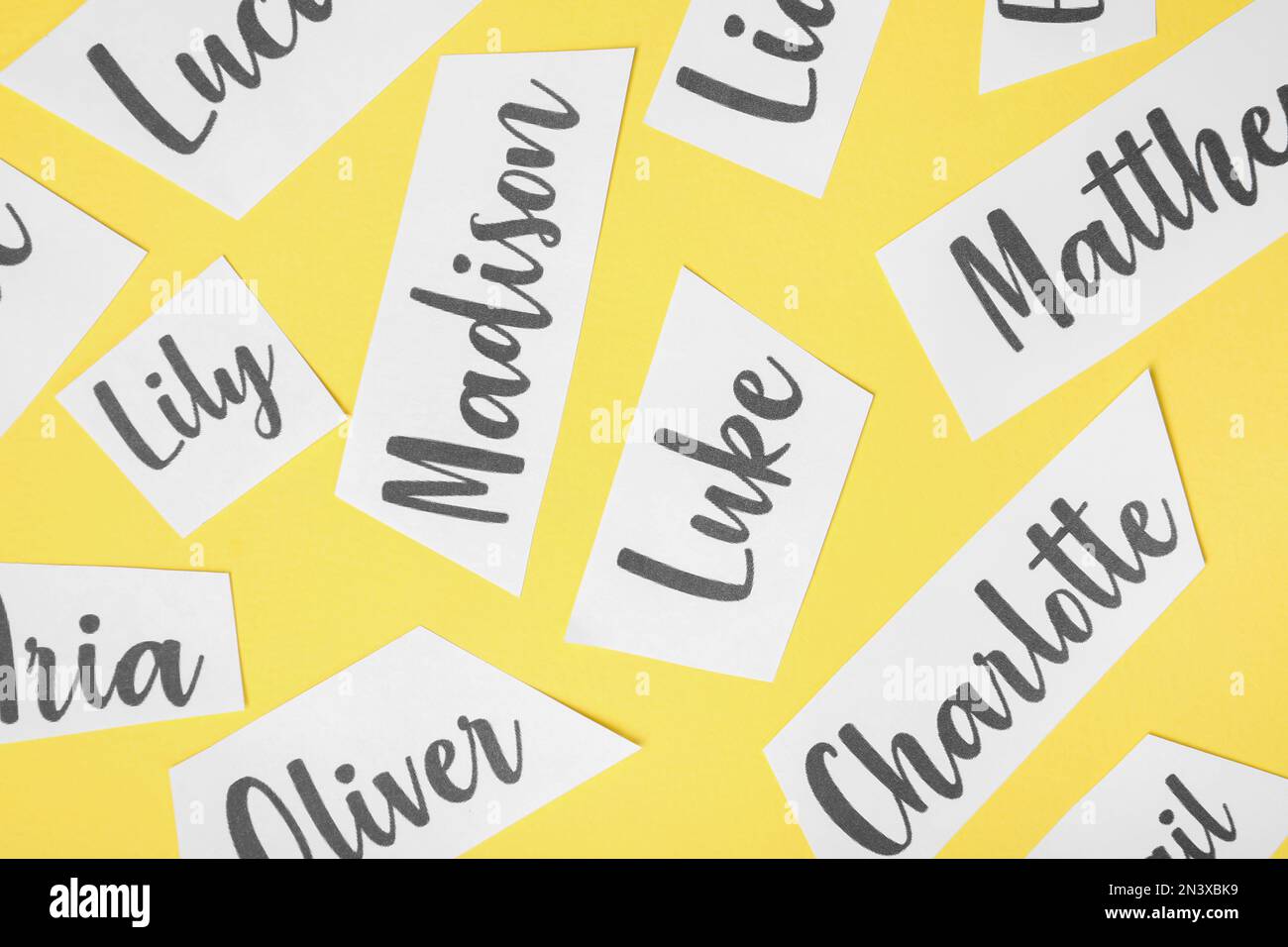 Paper sheets with written different baby names on yellow background ...