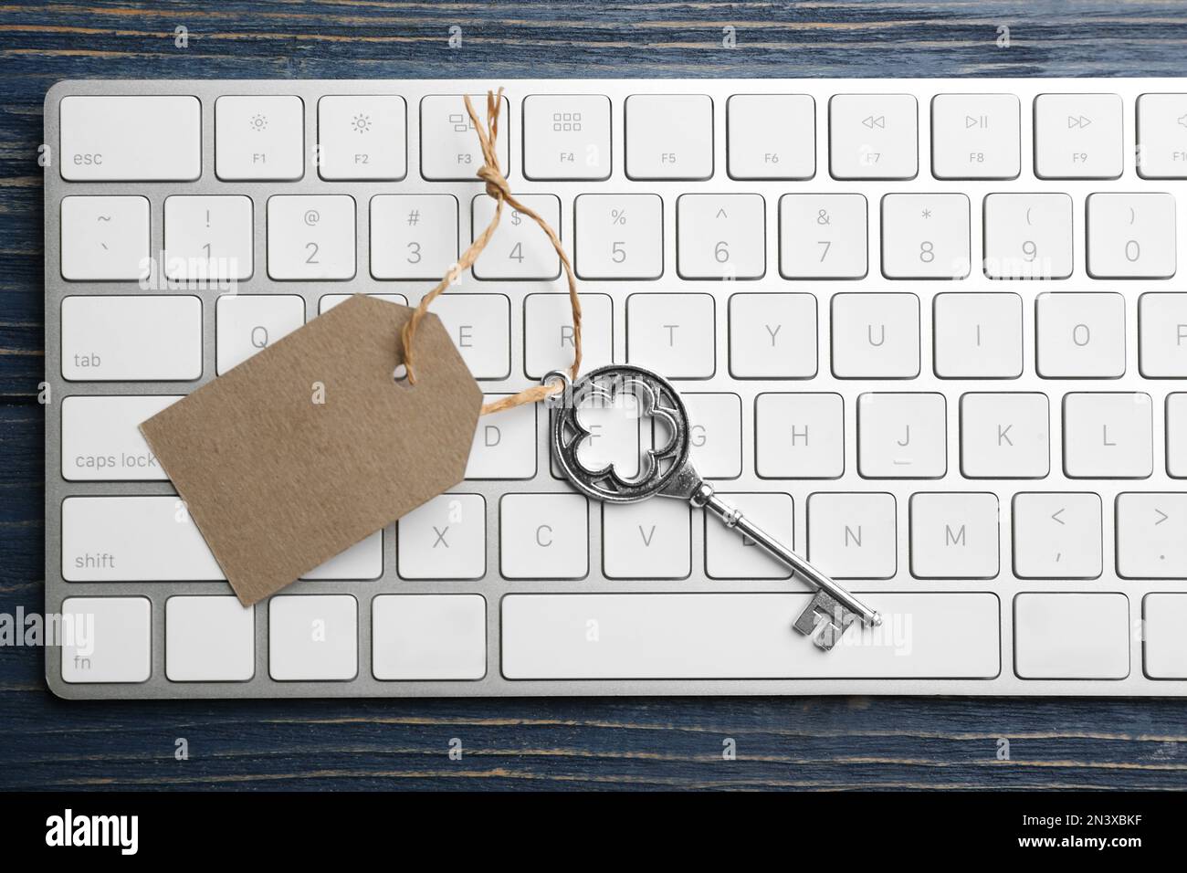 Key with blank tag and computer keyboard on blue wooden table, top view ...