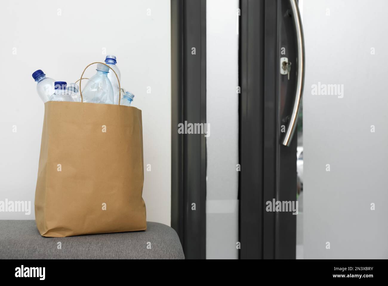 Paper bag with used plastic bottles near entrance door in hallway ...