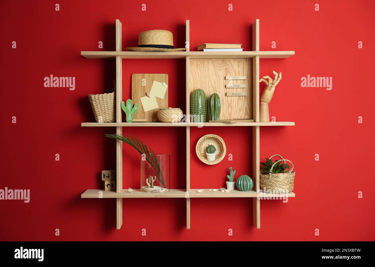 Stylish wooden shelves with decorative elements on red wall Stock Photo ...