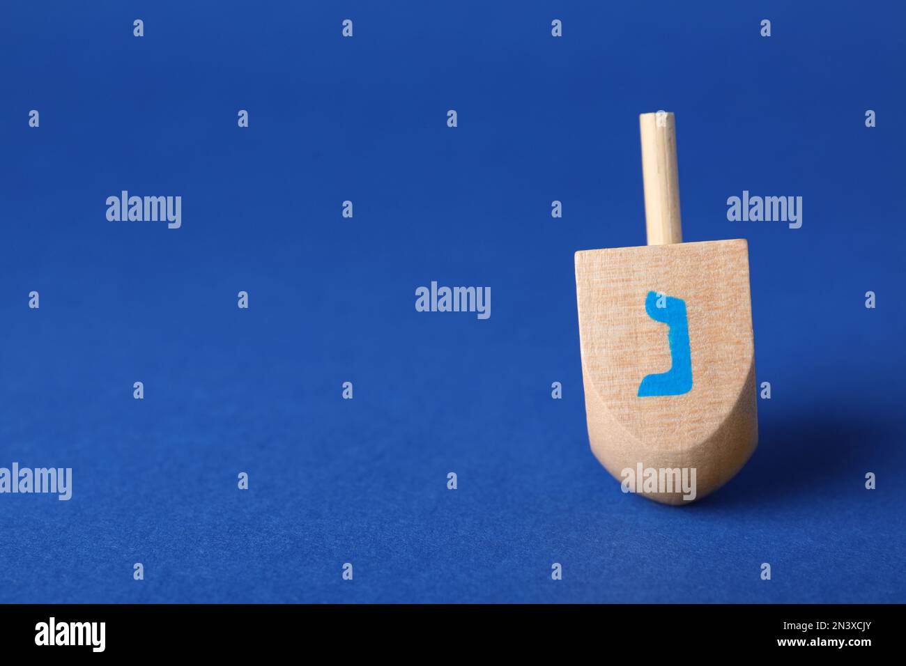 Hanukkah traditional dreidel with letter Nun on blue background, space ...