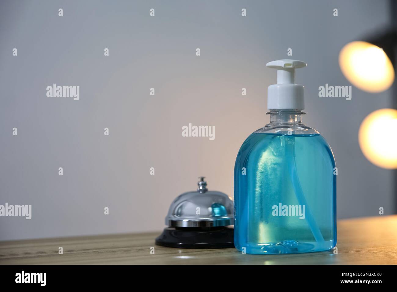 Dispenser bottle of antiseptic gel and service bell on reception desk ...