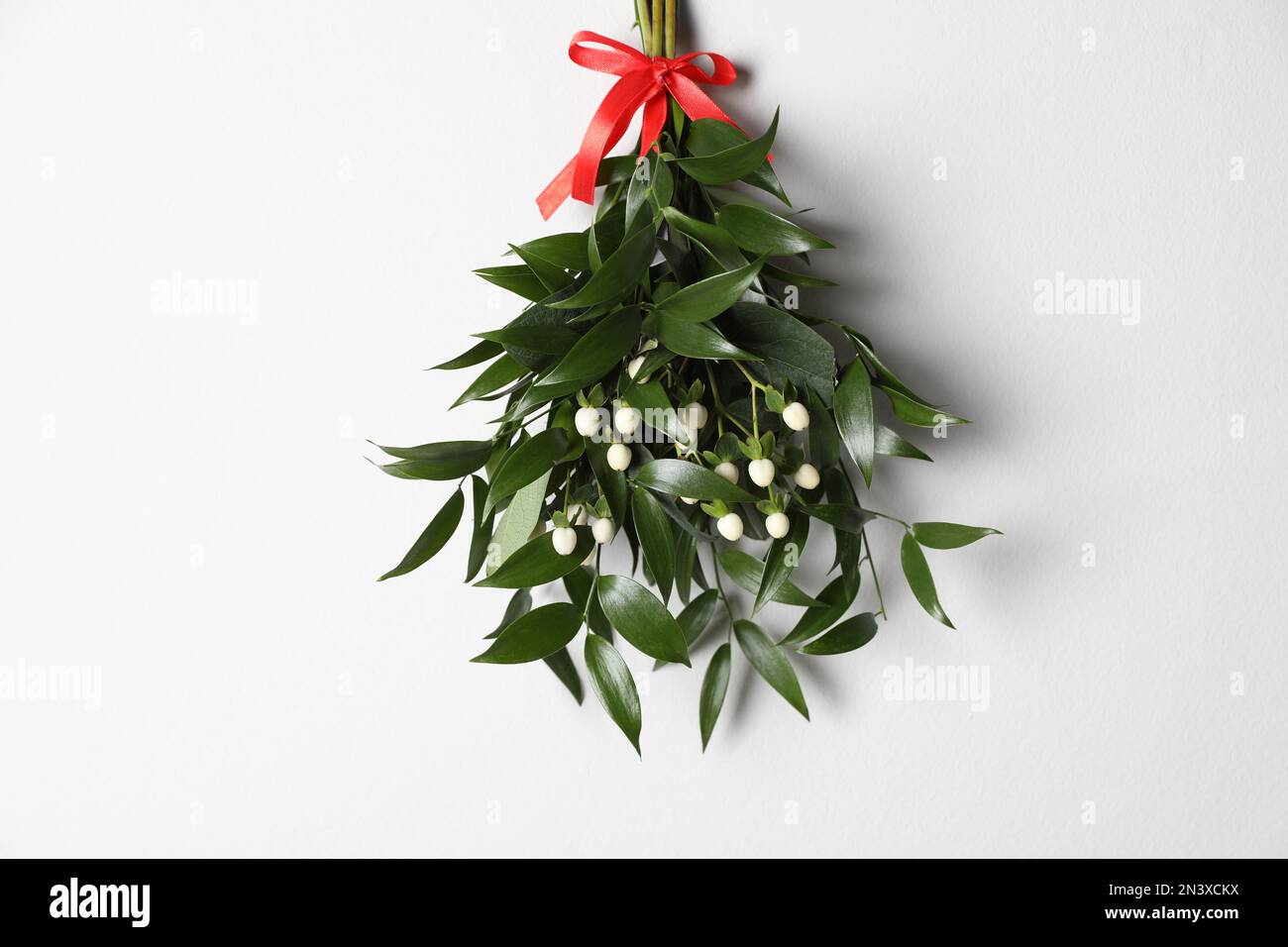 Mistletoe bunch with red bow hanging on white wall. Traditional ...