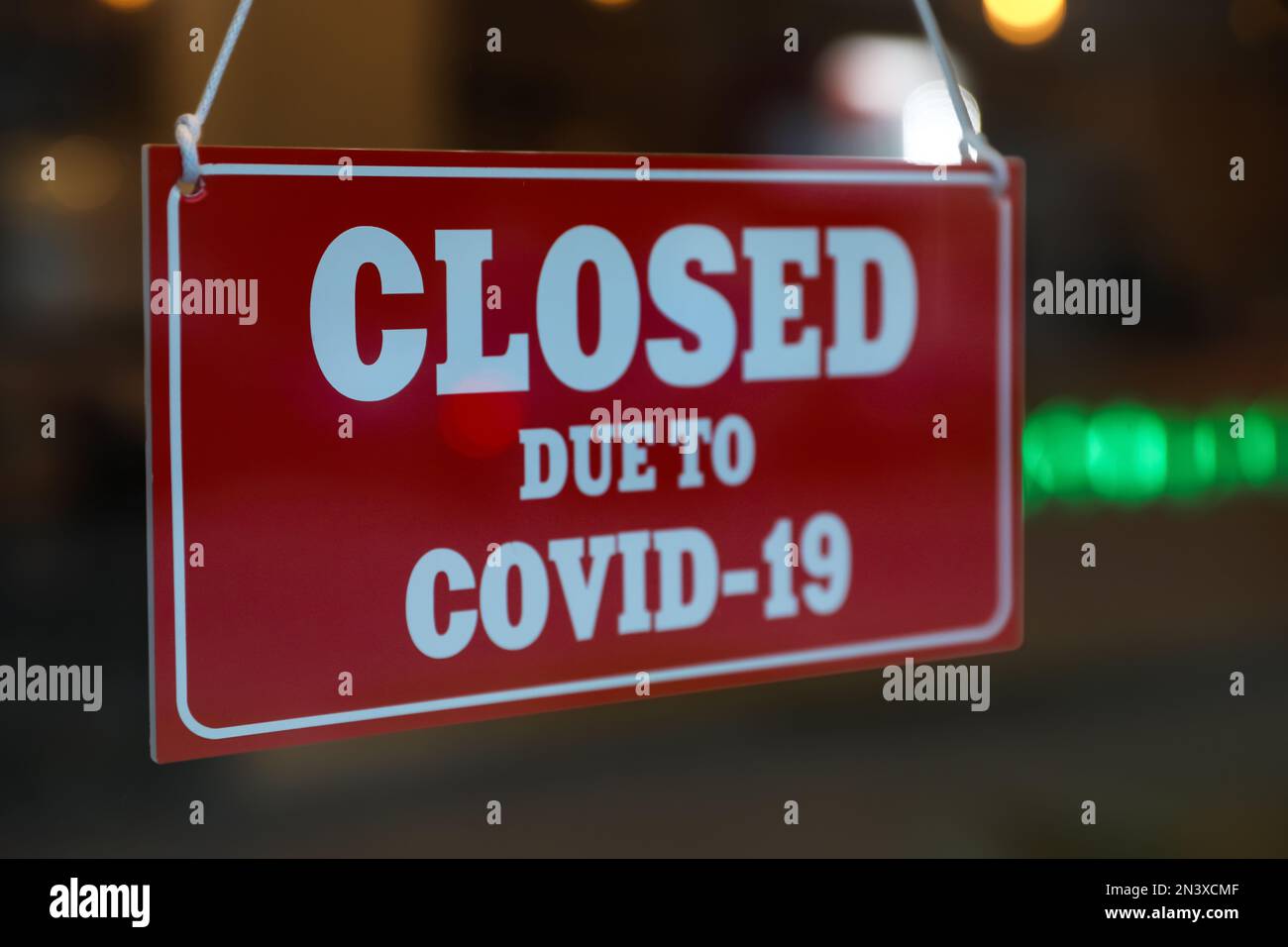 Red sign with words "Closed Due To Covid-19" hanging on glass door ...