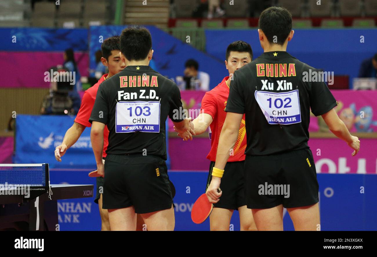 China's Ma Long, right wearing red, and teammate Zhang Jike shake hands ...