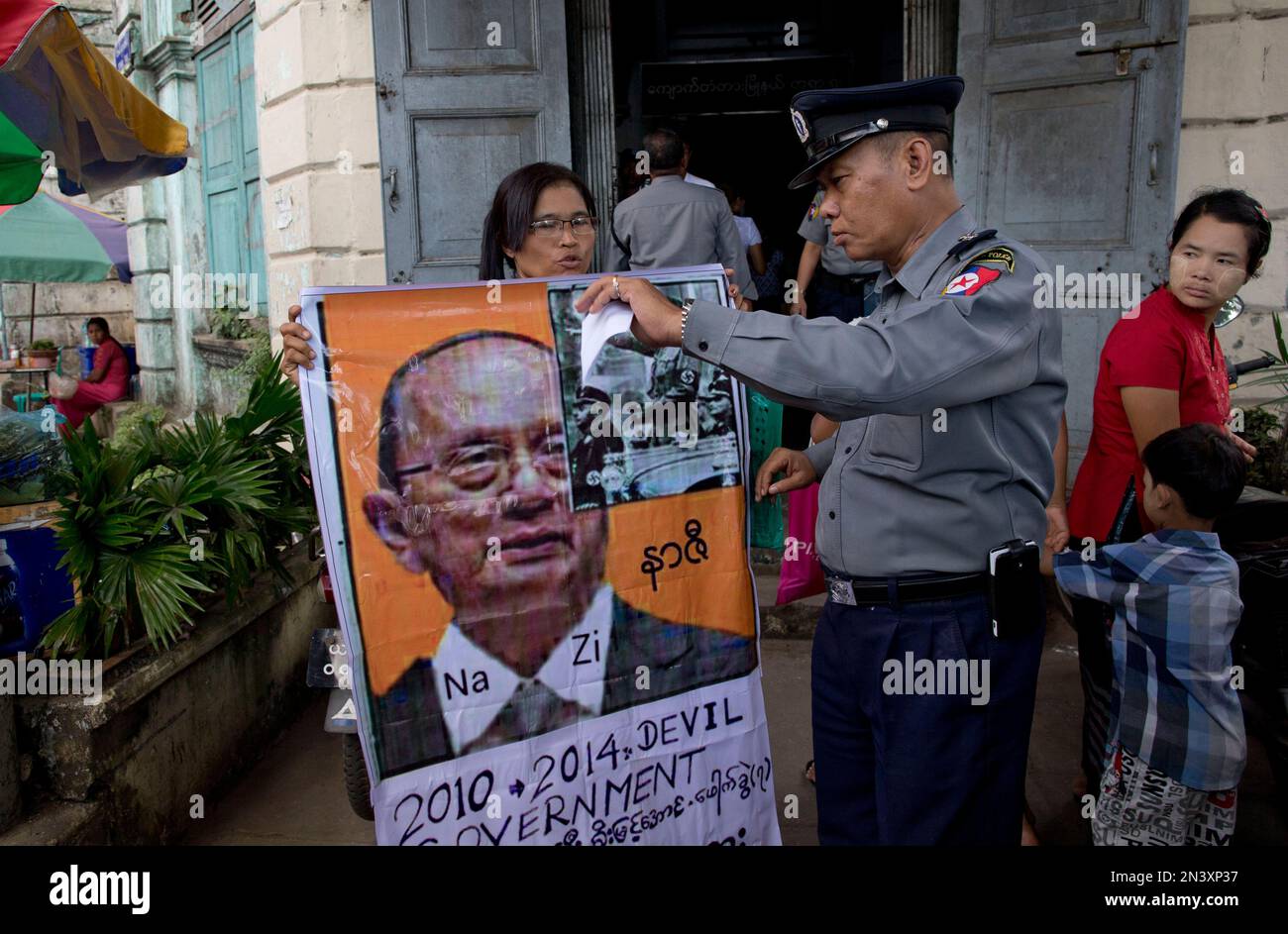 A police officer tries to usher away Civic Rights activist Sein Htwe who displays a poster ...