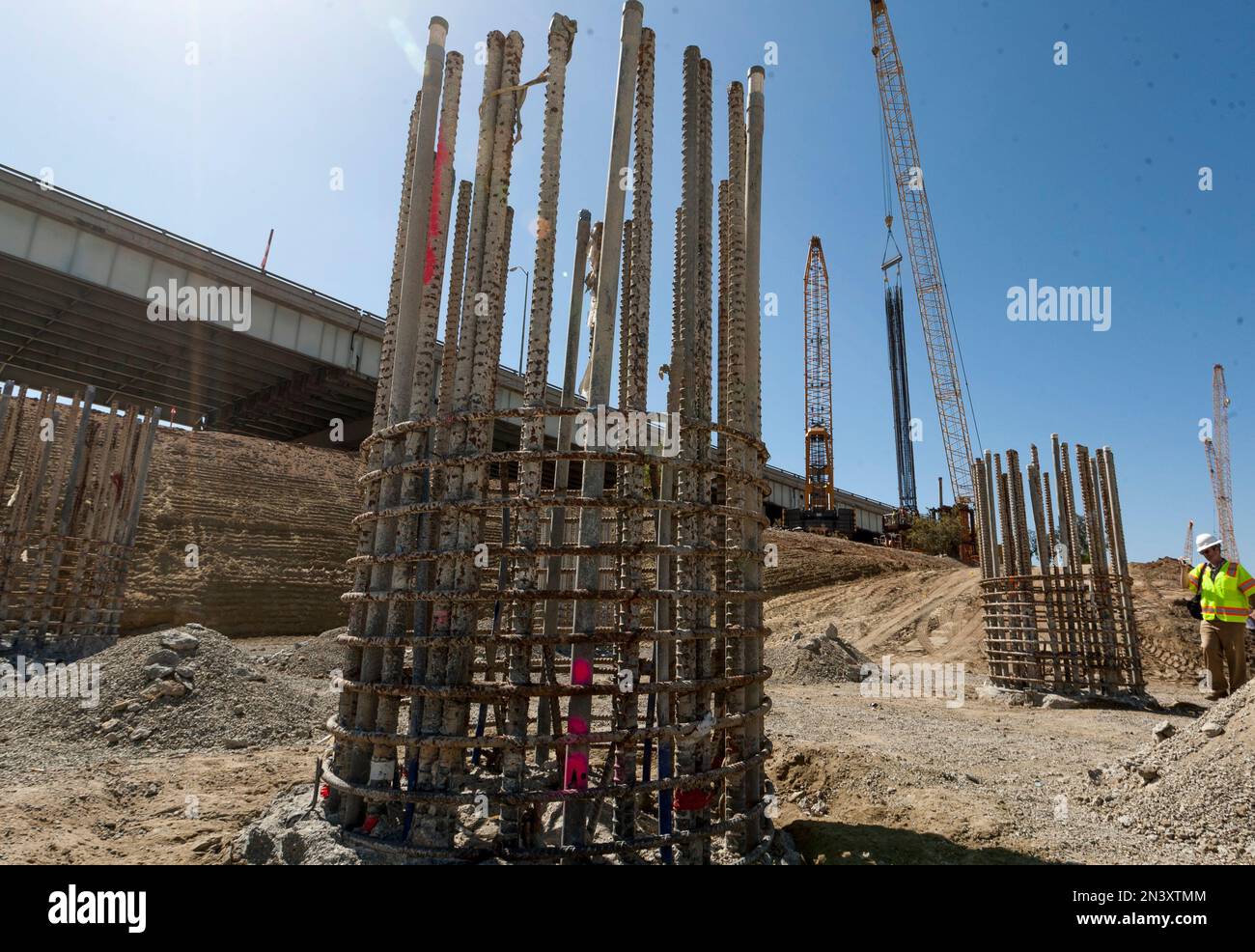 Poured concrete and inserted steel rebar in pre-dug holes protrude from ...