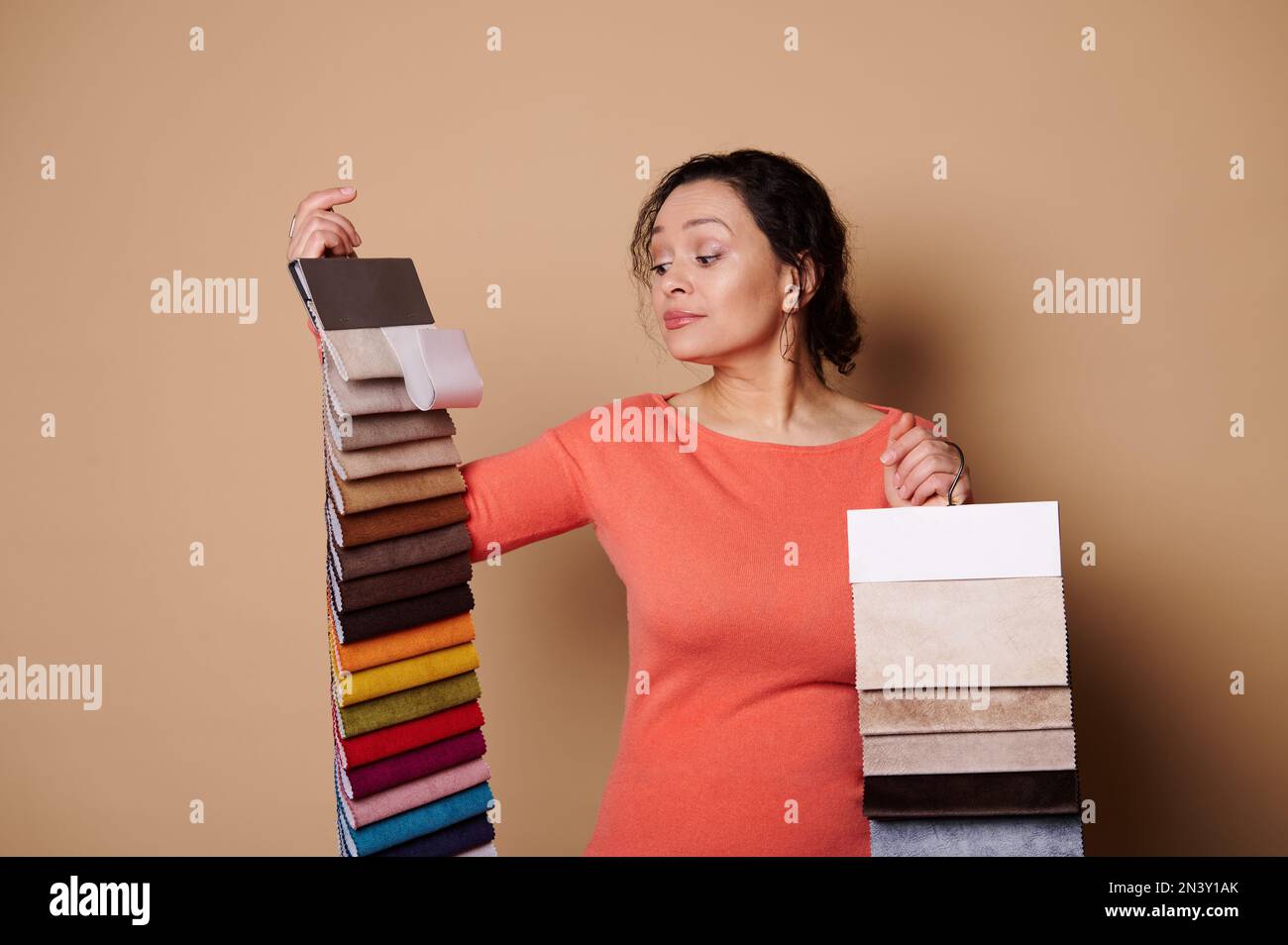 Multi-ethnic pretty woman holding fabric swatches of upholstery ...