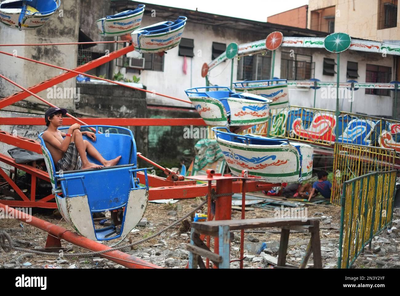 A Filipino worker rests on a carnival ride as they prepare to open at a ...
