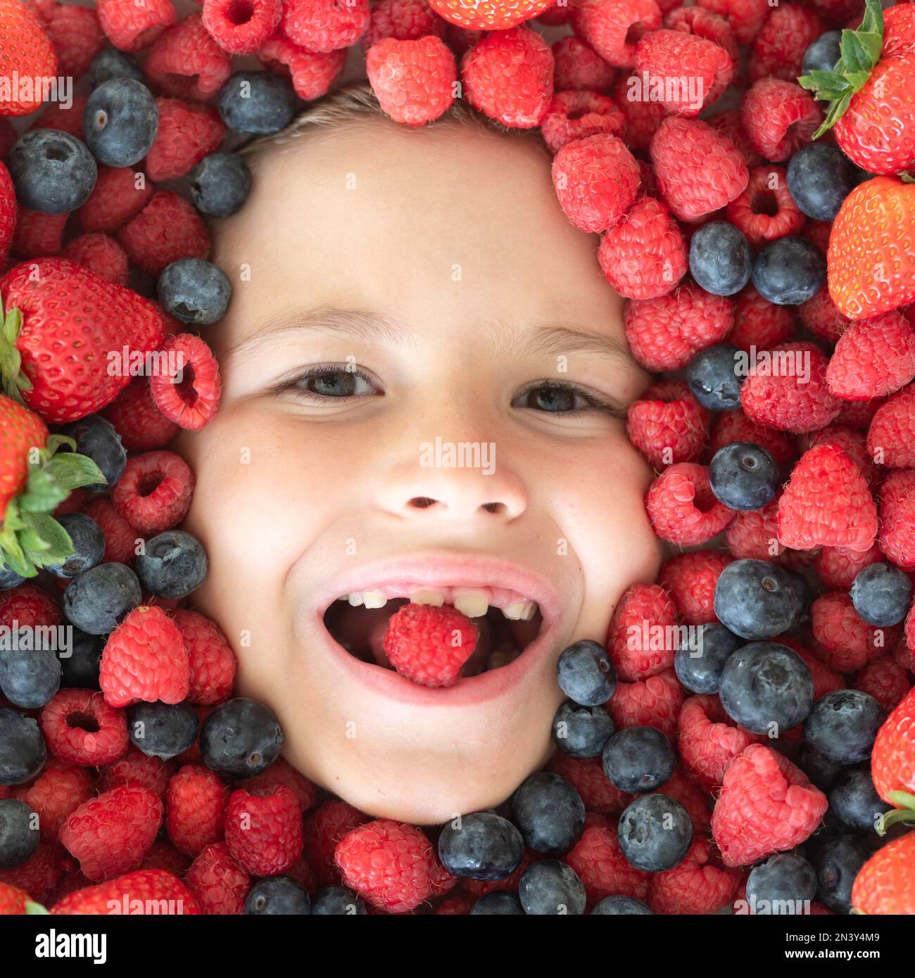 Healthy eating. Kids face with closeup berry. Berries mix of strawberry ...