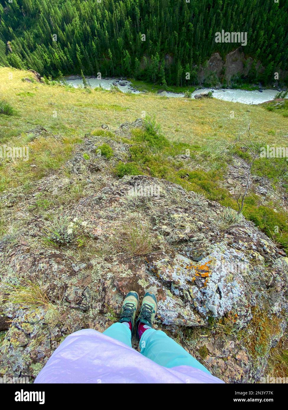 View down on the legs and trekking shoes of a traveler girl standing on alpine stones Stock ...