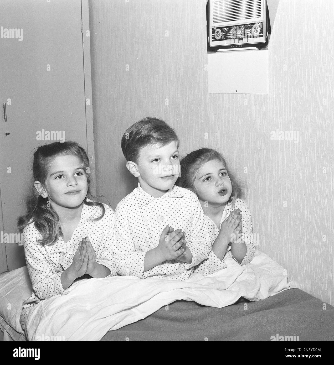 In the 1950s. Three children in bed at bedtime saying their evening ...