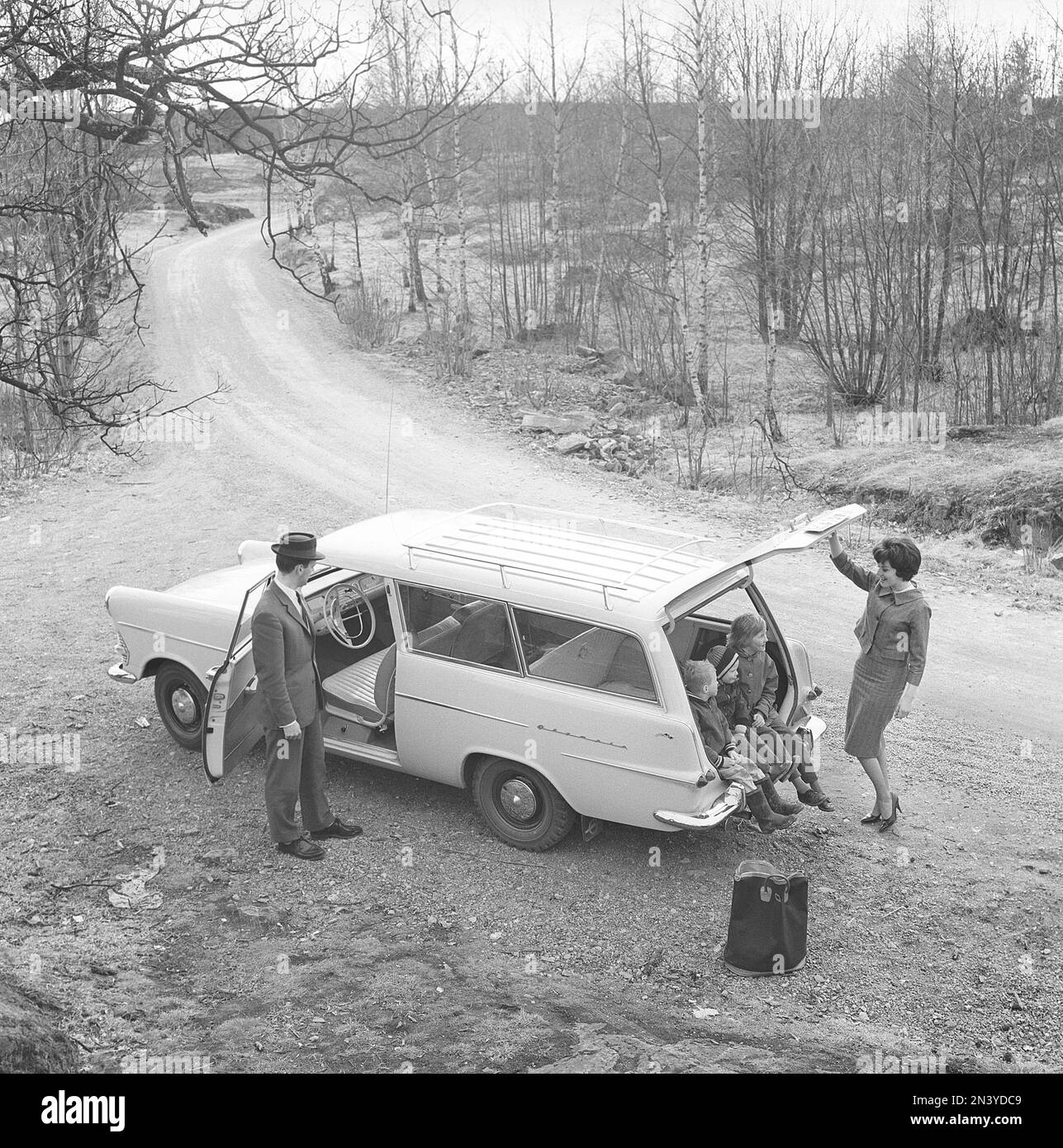 Driving in the 1960s. A family with their car, an Opel Olympia, a ...