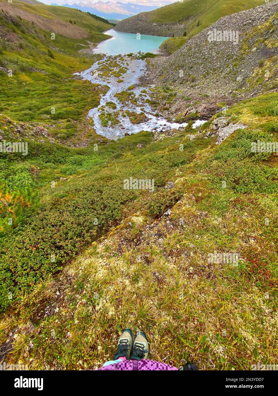 View down on the legs and trekking shoes of a traveler girl standing on ...