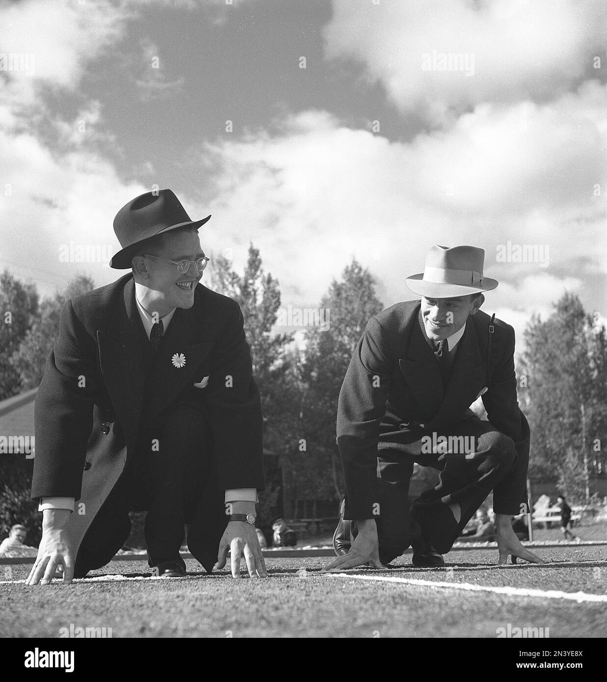 1940s men. Two men in suit and hats are seen on the startline of a ...