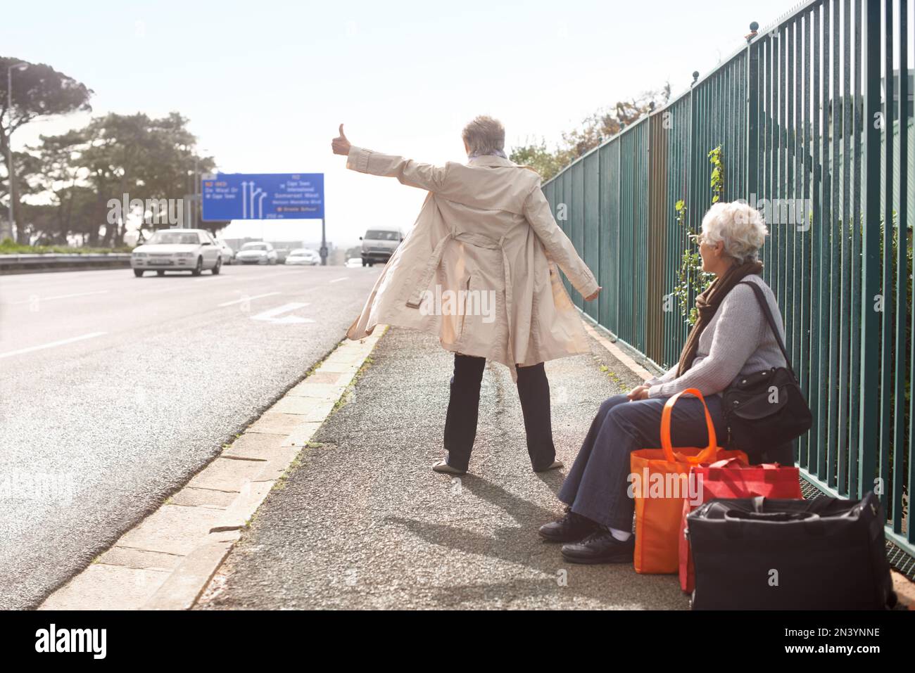 Never too old for an adventure. Two senior women hitchhiking along a ...