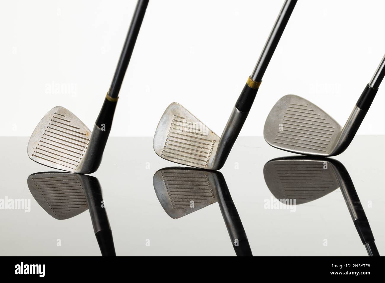 Close up of three golf clubs with copy space and reflection on white ...