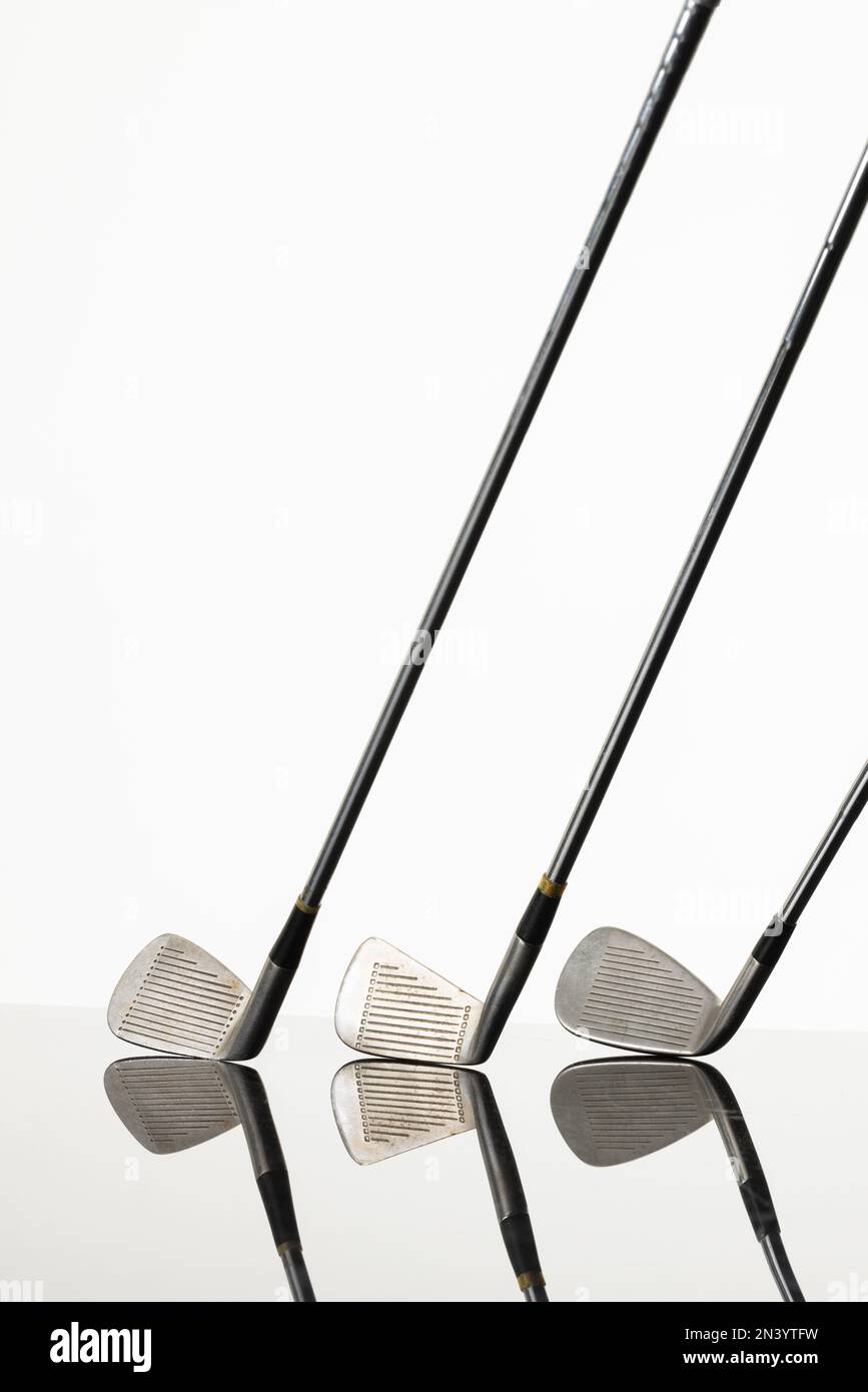 Close up of three golf clubs with copy space and reflection on white ...
