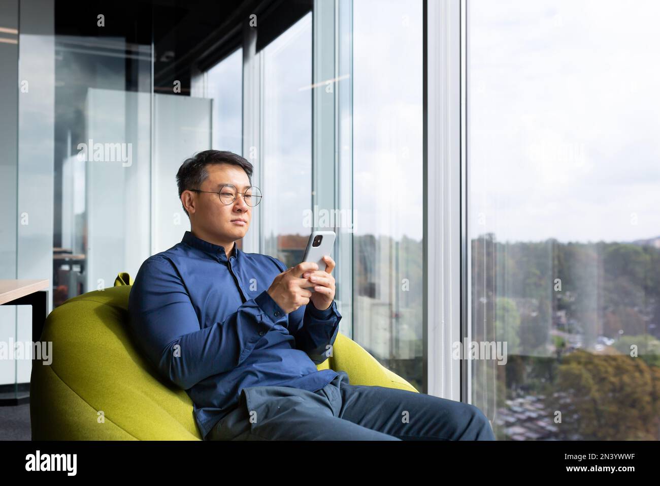 Serious thinking asian man reading news on phone, programmer using app ...