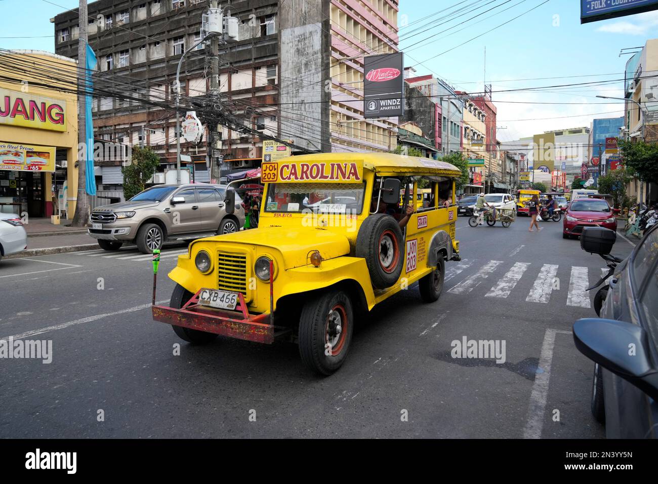 A vintage passenger jeepney passes by a road just outside what used to ...
