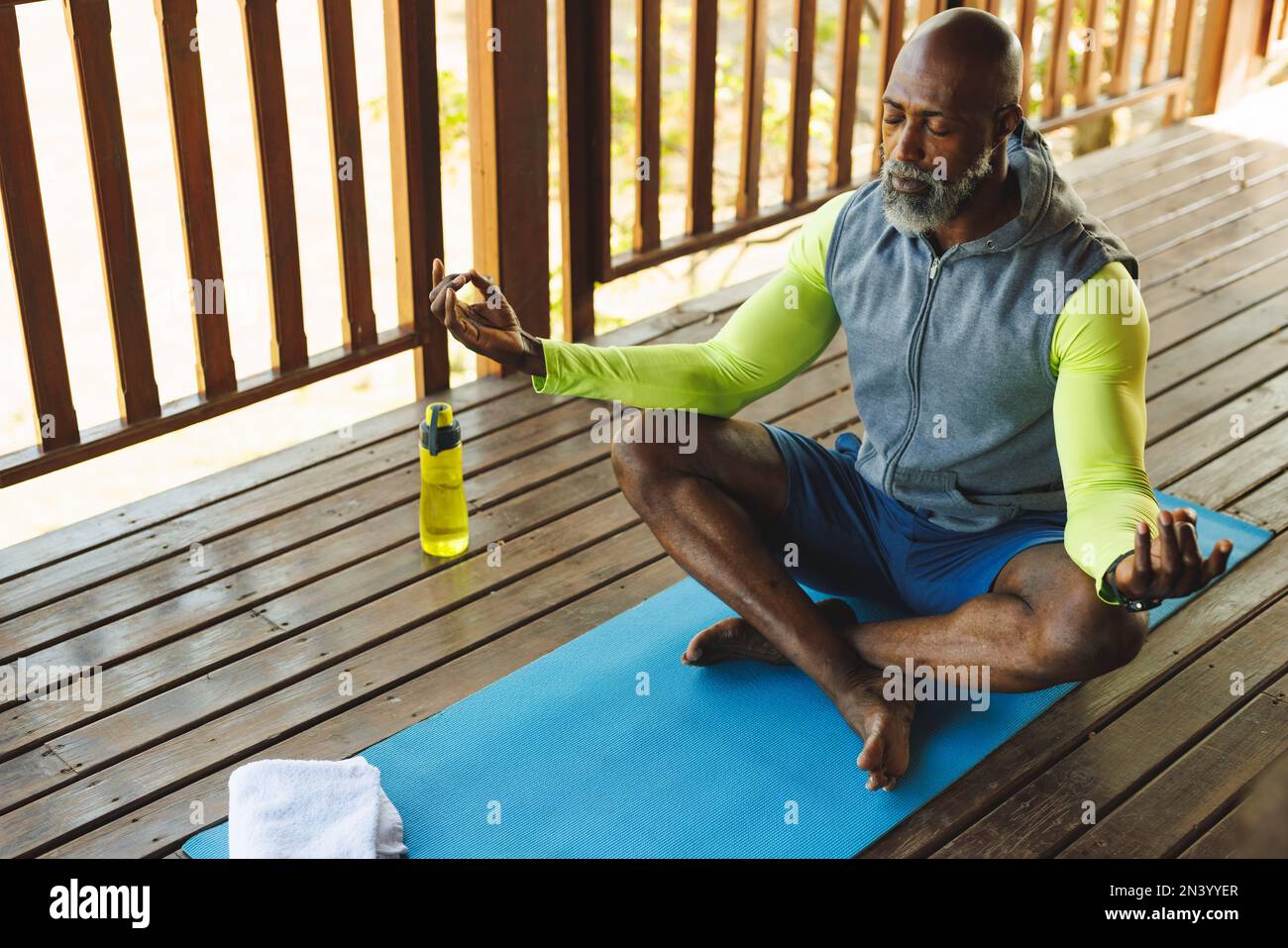 High angle view of african american senior man meditating on mat in balcony at log cabin Stock ...
