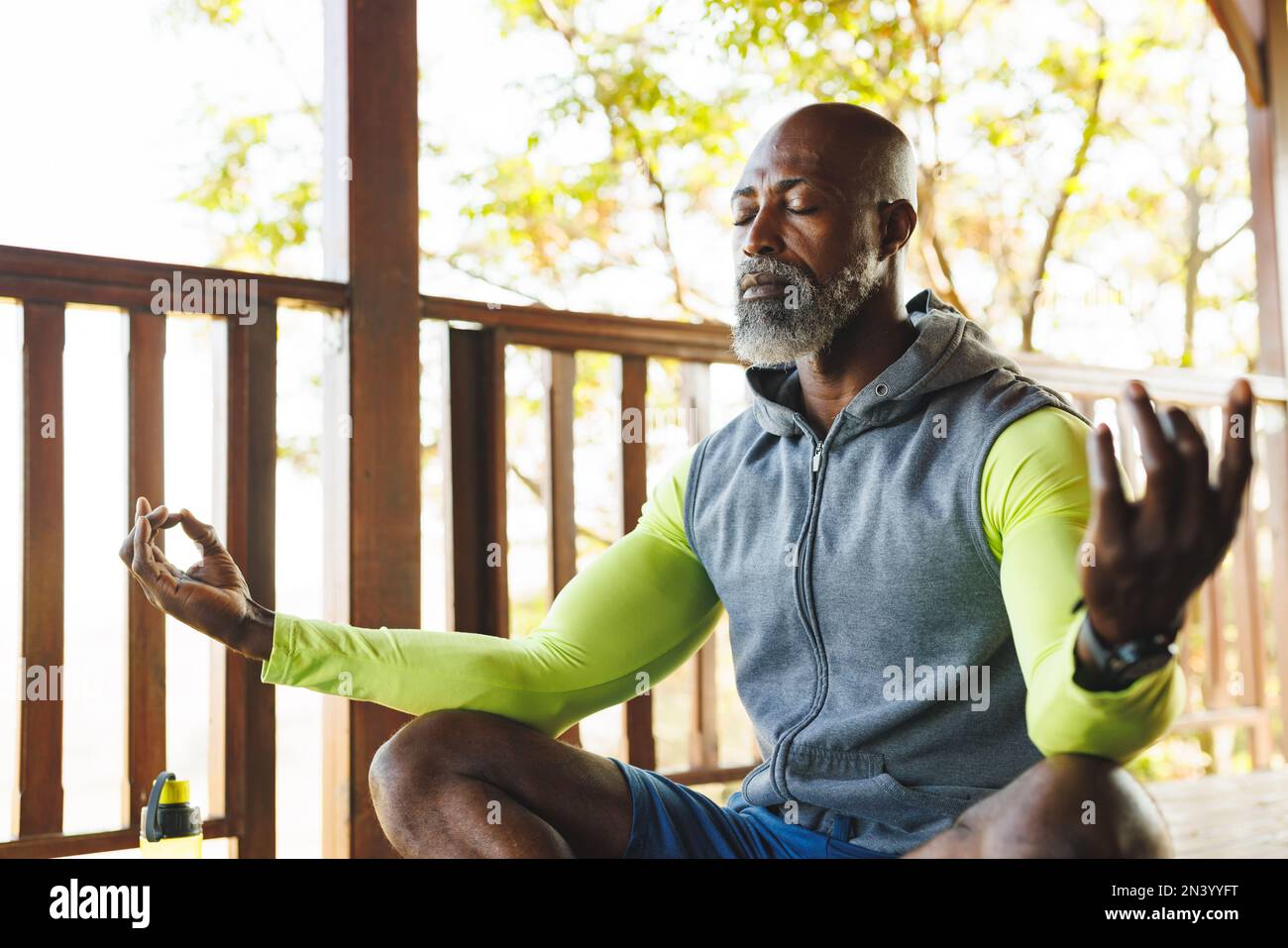 Bald african american senior man with eyes closed meditating in balcony at log cabin Stock Photo ...