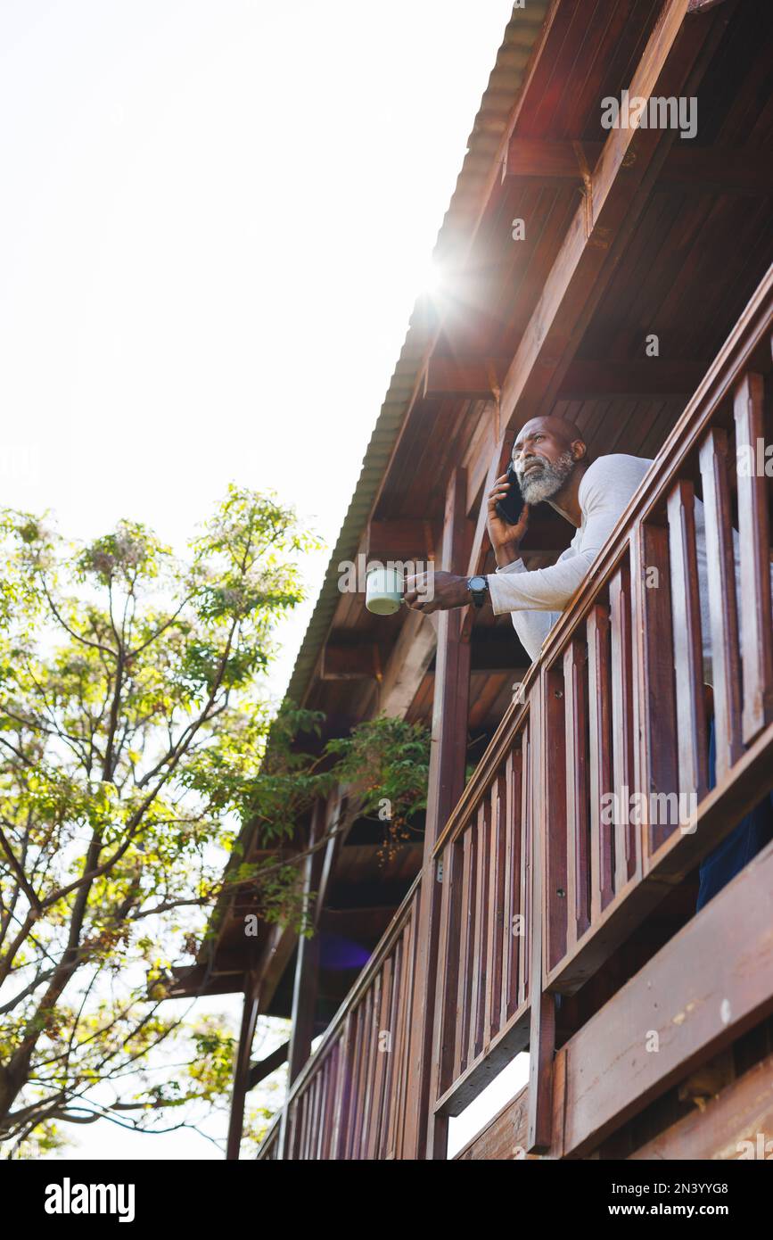 Low angle view of african american senior man with mug talking over ...