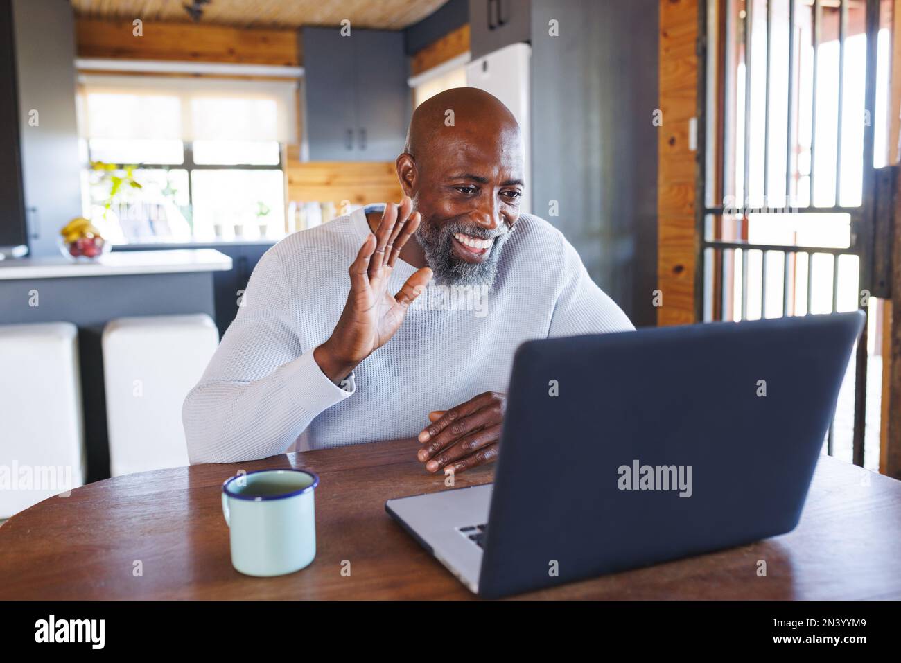 Happy african american senior man waving hand while talking over video ...