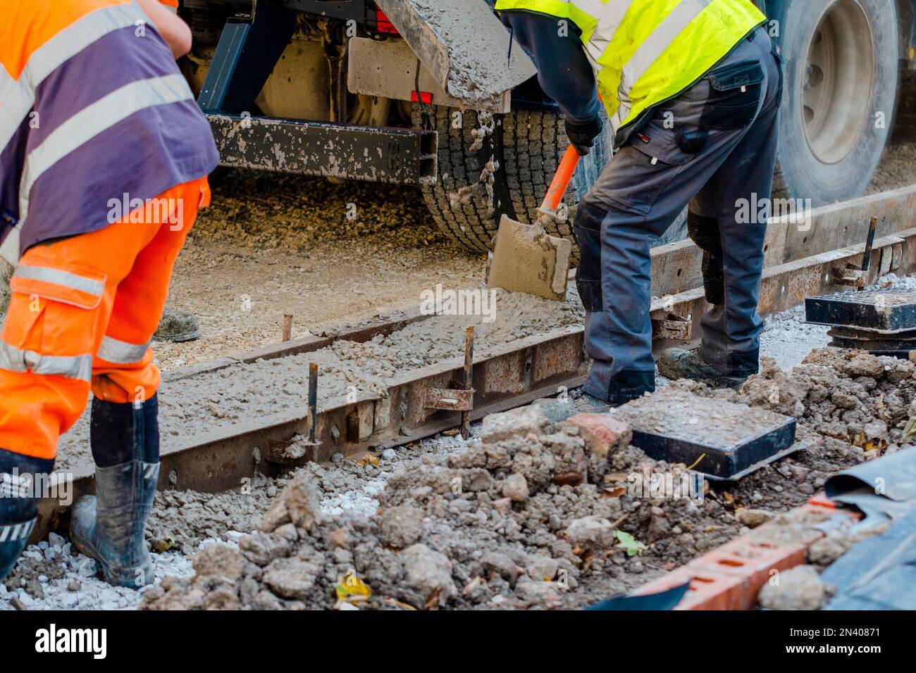Builder pouring ready-mix concrete into formwork, levelling it and ...