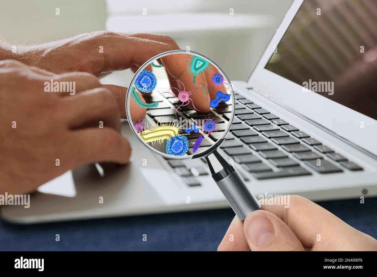 Man with magnifying glass detecting microbes on laptop keyboard ...