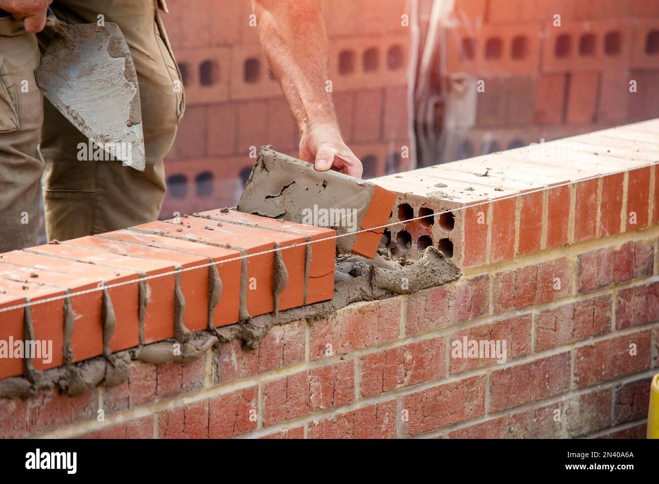 Industrial bricklayer laying bricks on cement mix on construction site ...