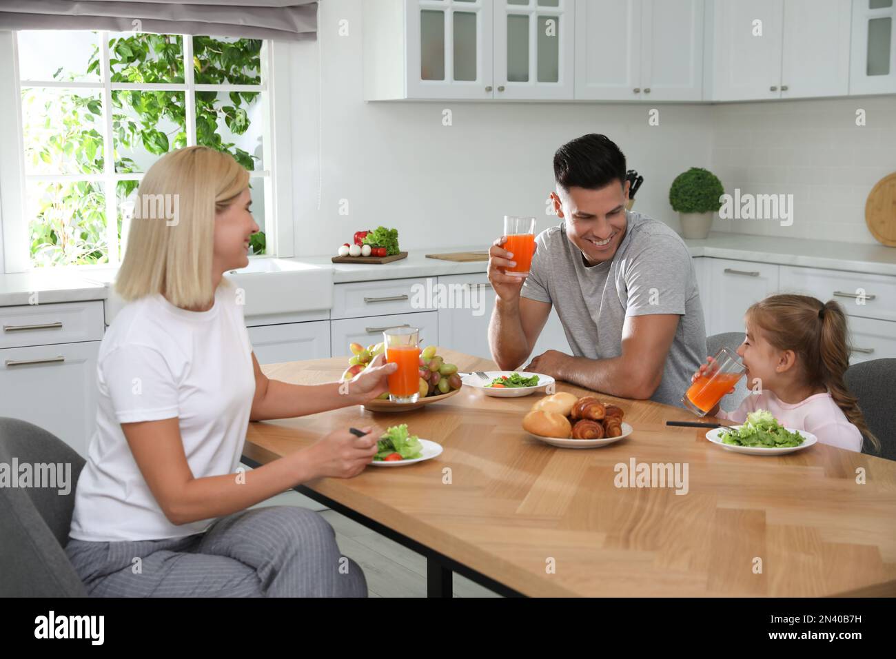 Happy family having breakfast together at table in modern kitchen Stock ...