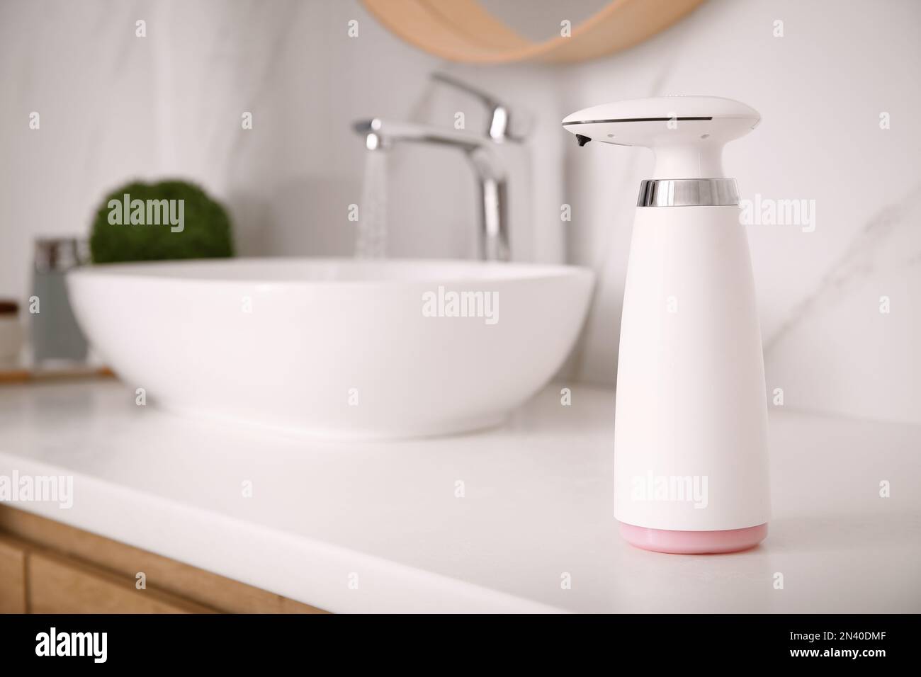 Modern automatic soap dispenser on countertop in bathroom. Space for ...
