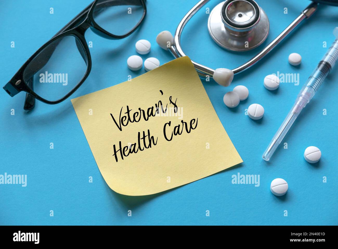 A glasses, pills, syringe, stethoscope and yellow memo sticky note ...